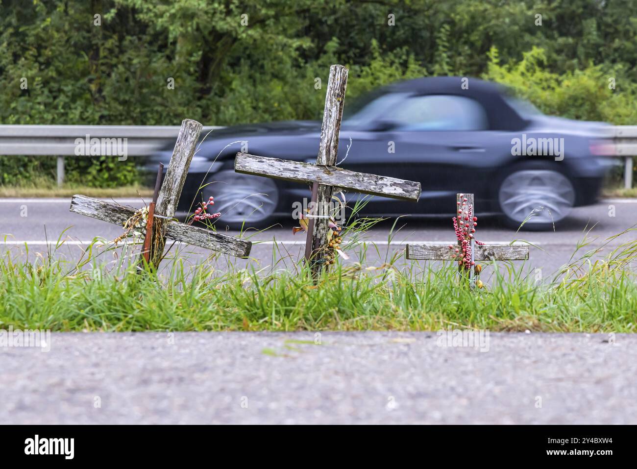 Cross on a country road, symbol of remembrance for three road accident ...