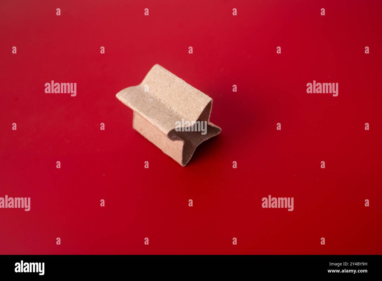 a single, folded piece of brown toilet paper roll on a plain red ...