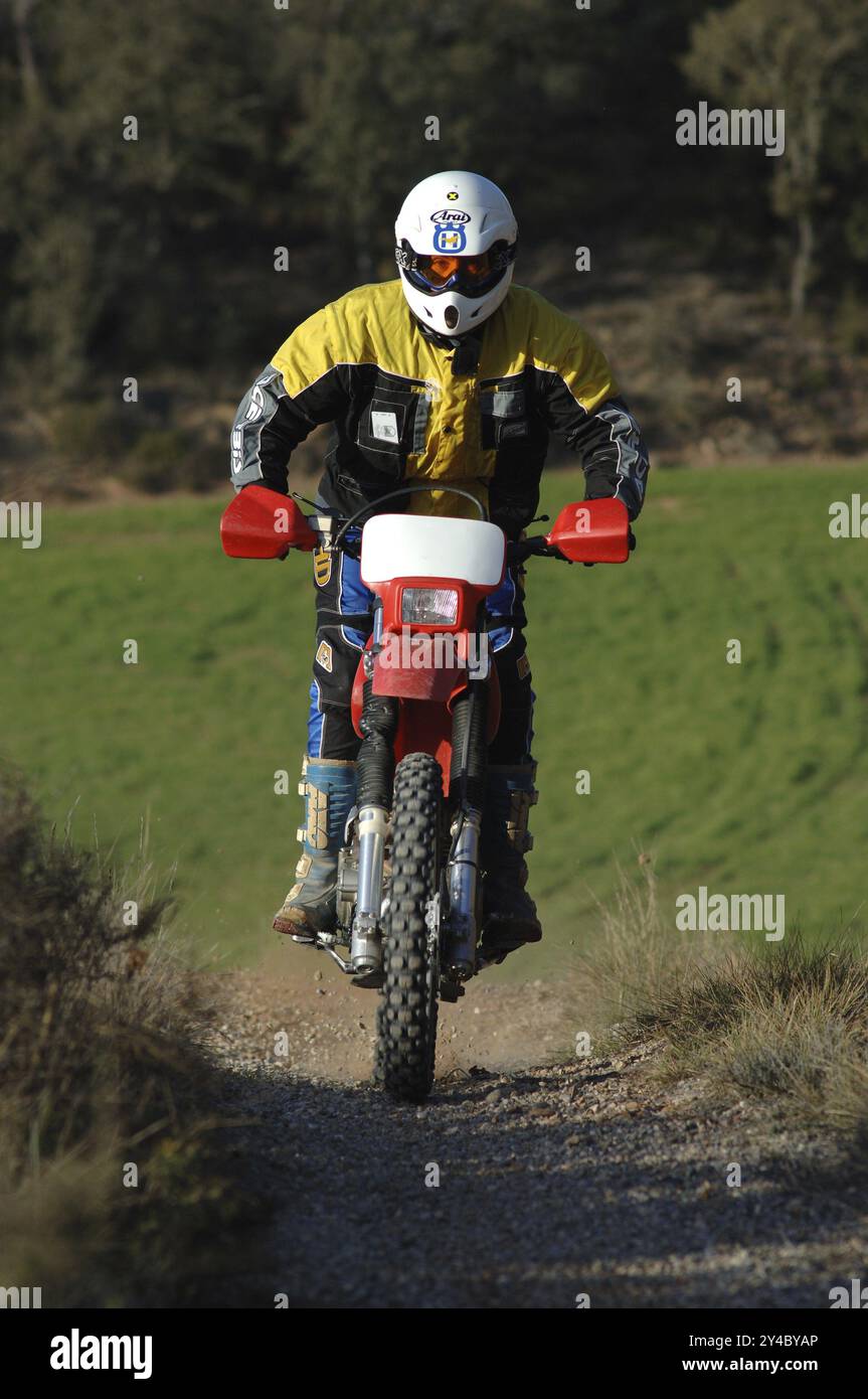 Female motorcyclist, standing in the rests, off-road, colourful clothes ...