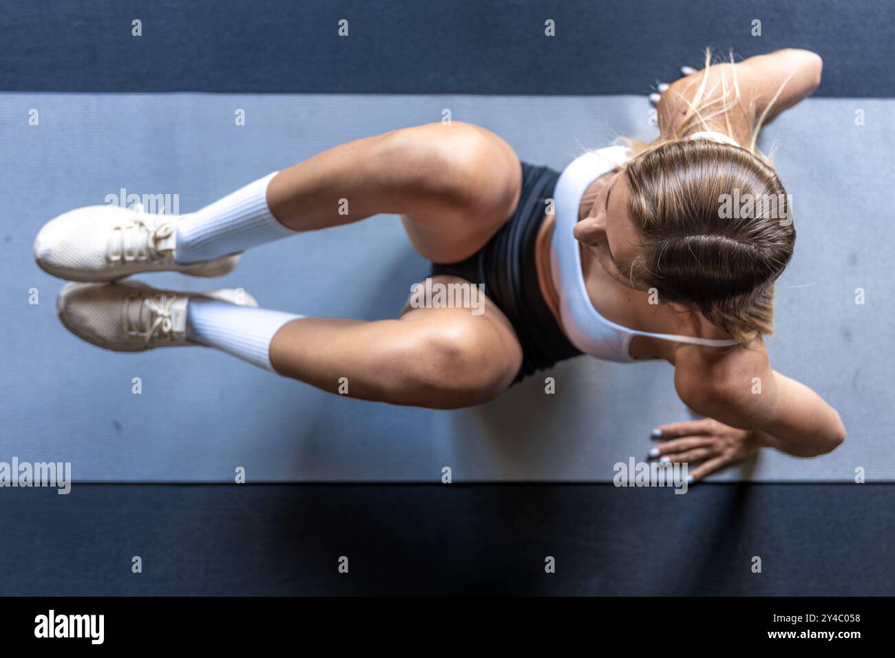 Sporty girl sits on a mat in the gym. Sports exercises and a healthy ...