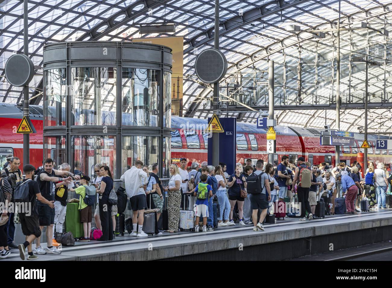 Central station with glass roof construction, crowds of people on the platform, regional train ...