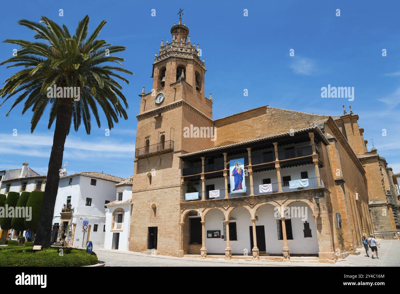 Historic church with bell tower and palm trees under a bright blue sky ...