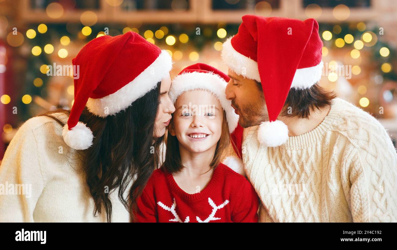 Parents in santa hats kissing daughter on Christmas eve Stock Photo - Alamy