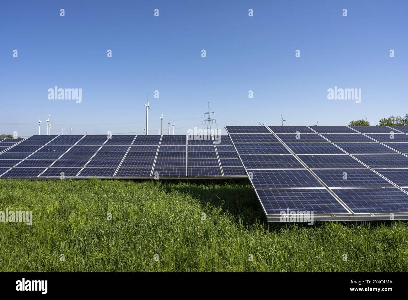 Solar system with power lines and wind turbines in the background, seen ...