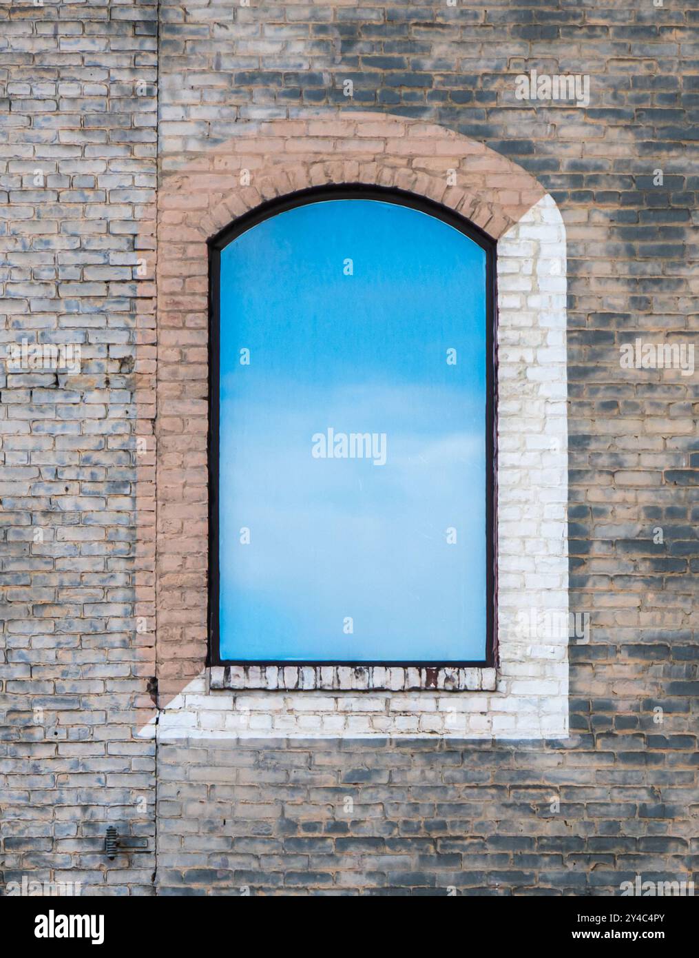 Arched window in building facade with sky visible through the window ...