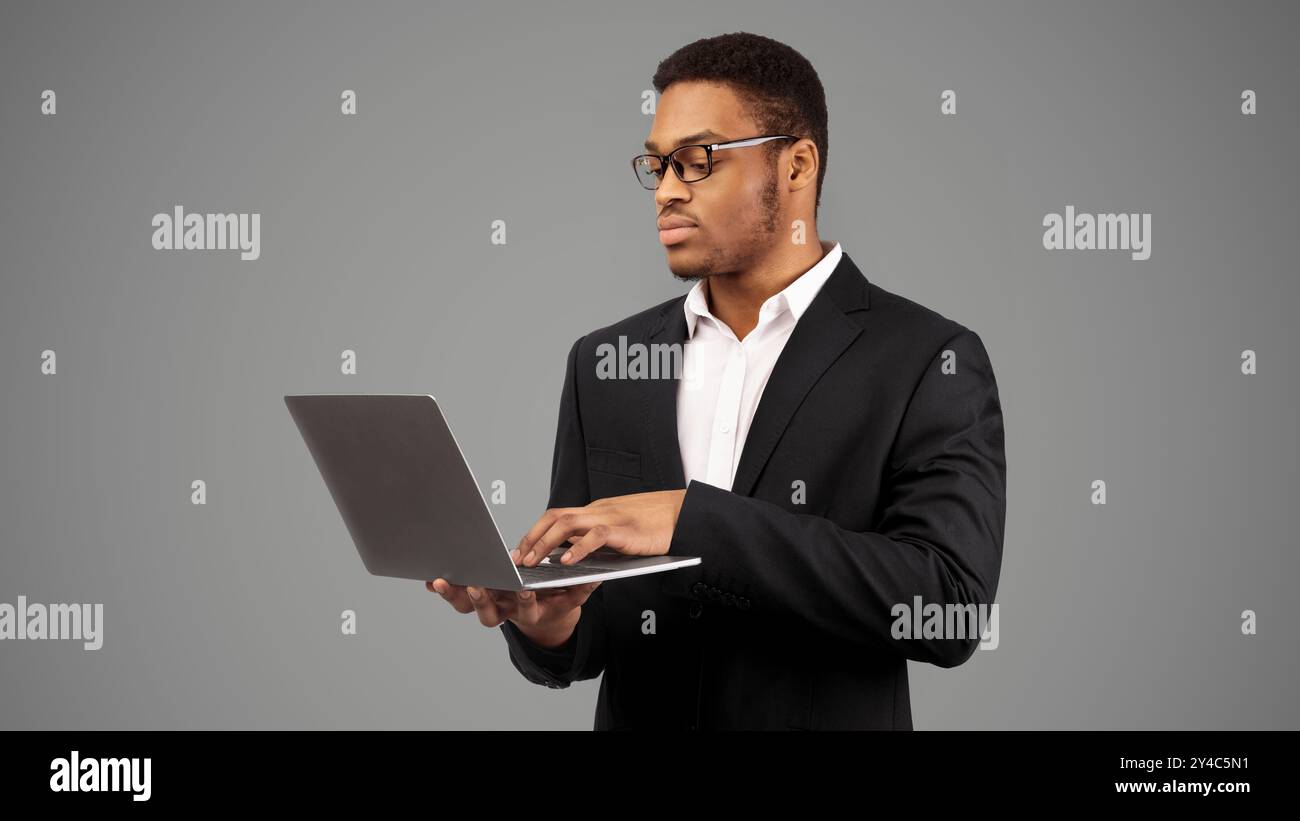 Serious black guy with laptop over studio background Stock Photo - Alamy