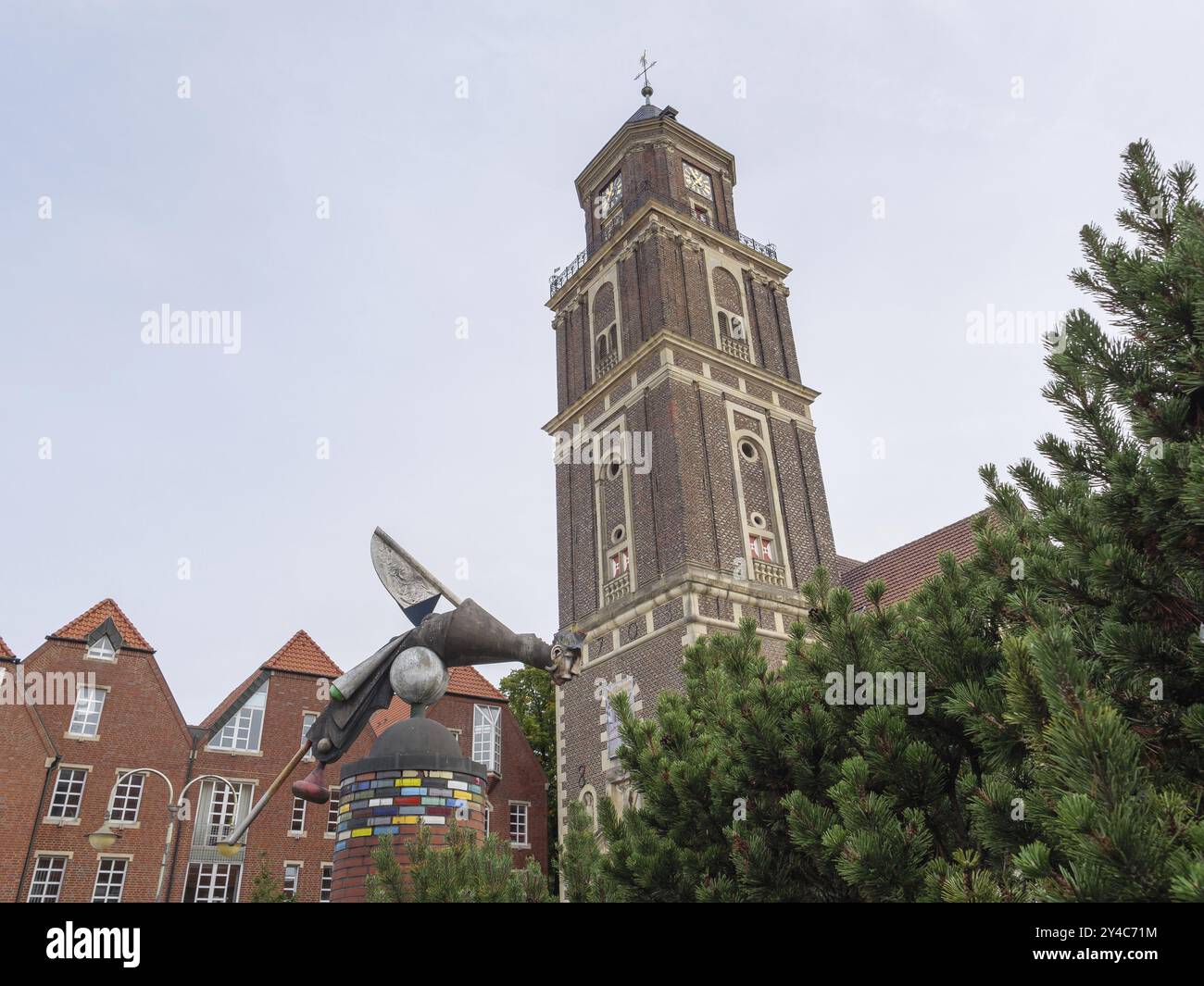 Large bell tower and a modern sculpture in front of historic brick ...