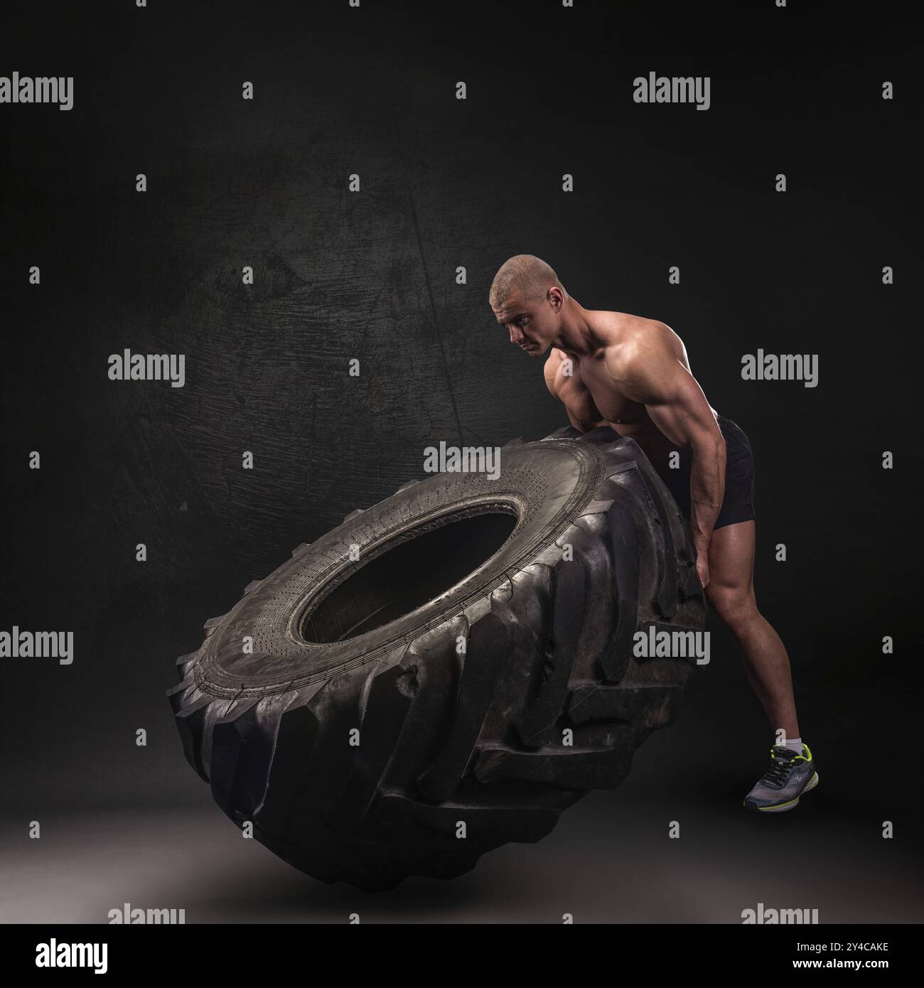 Sportsman lifting large heavy wheel in a gym Stock Photo - Alamy