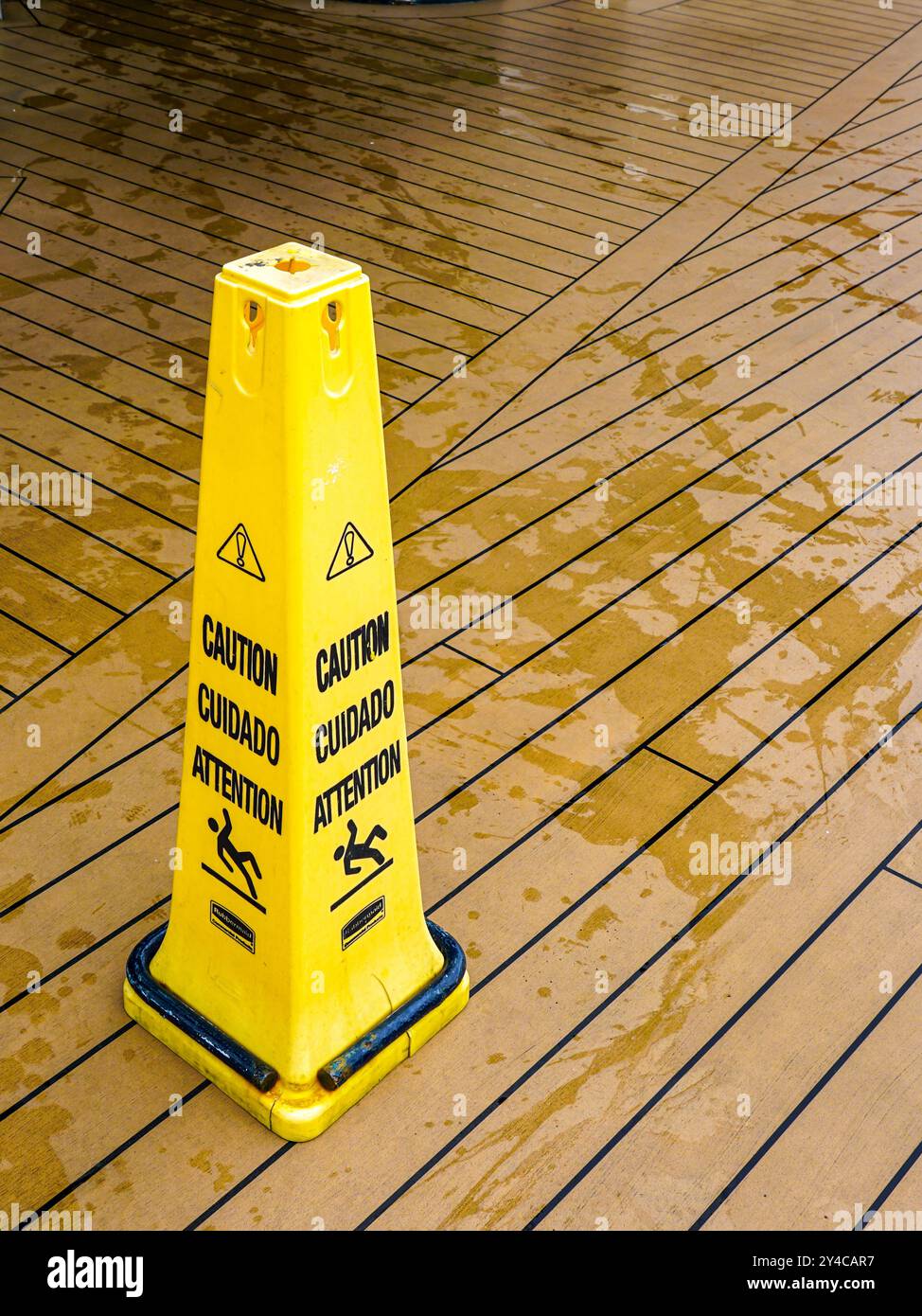 A yellow plastic warning pylon about the slippery wet floor on the deck ...