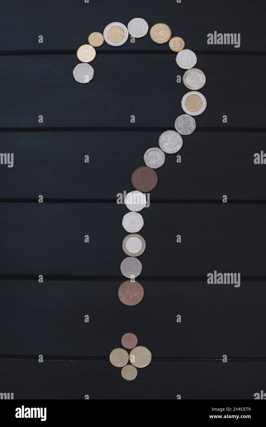 Scattered coins of different countries in the form of a question mark ...