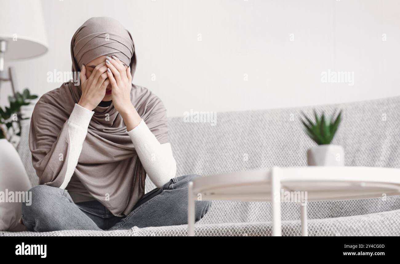 Crying muslim woman in hijab sitting on sofa at home Stock Photo - Alamy
