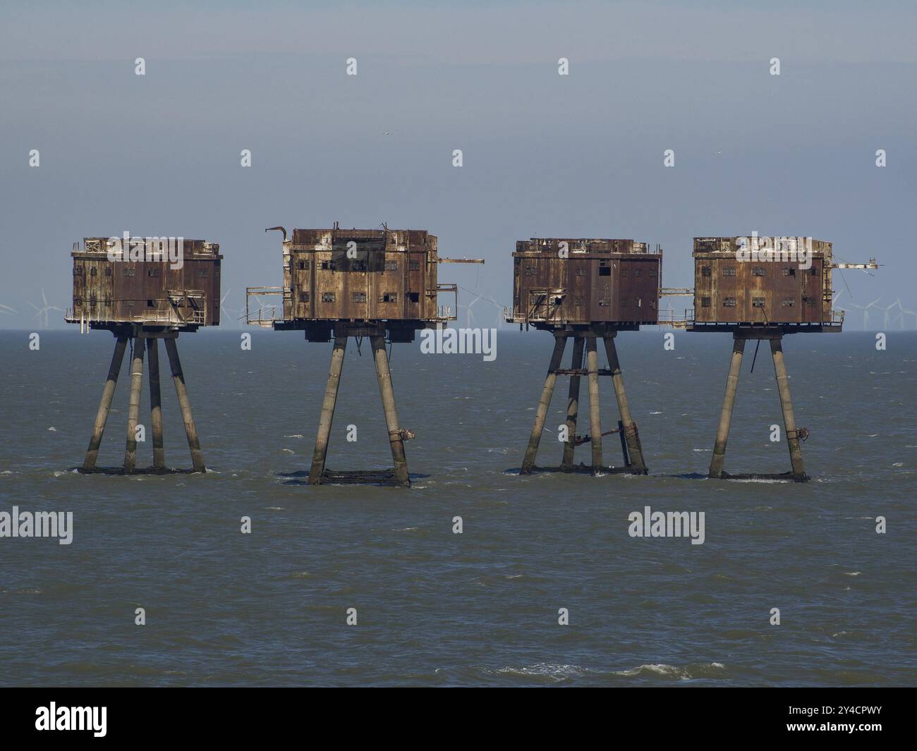 Close-up of four rusty sea houses on stilts in the sea, themse ...
