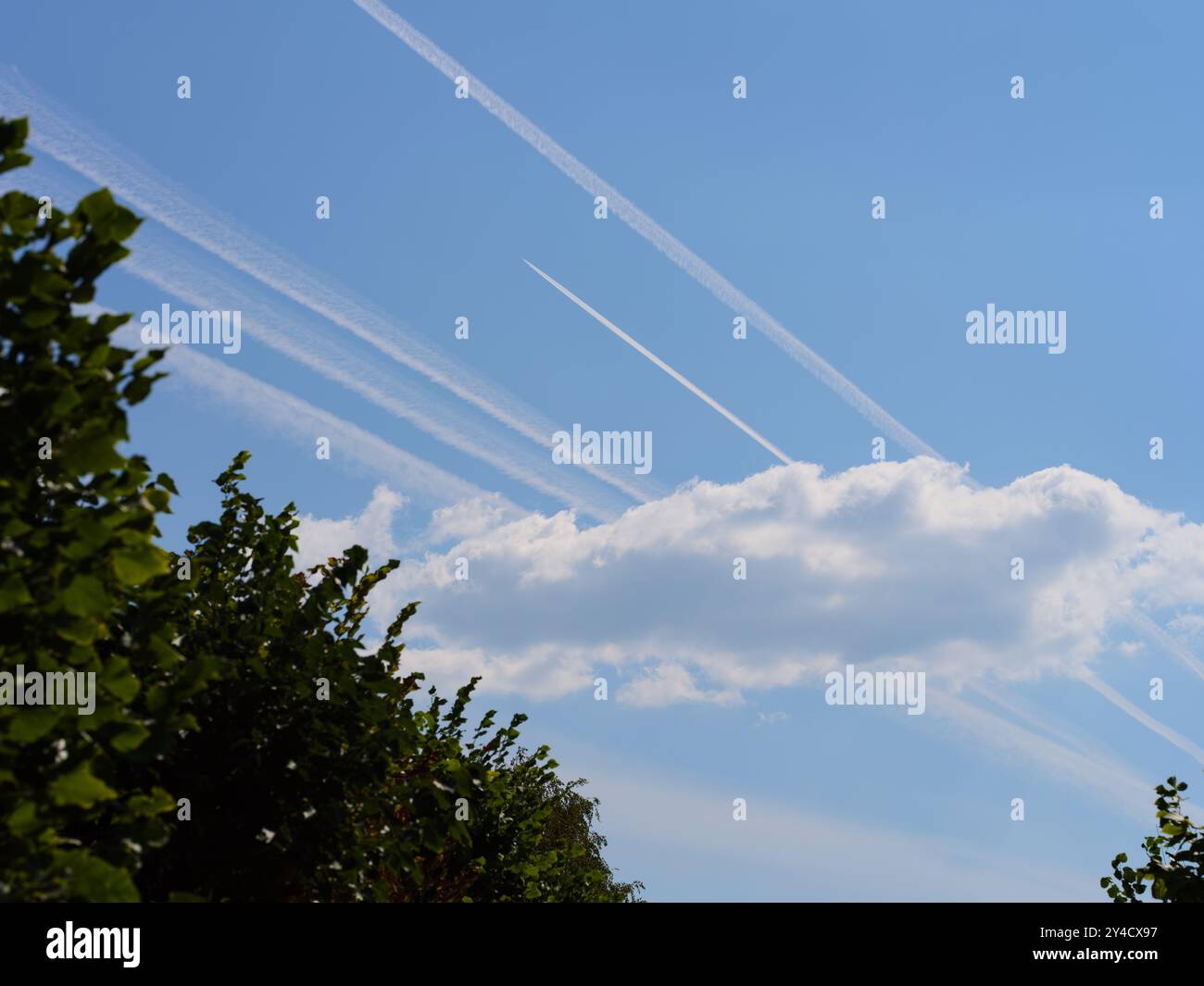 Airplane condensation trails (contrails) in the blue sky going out of a ...
