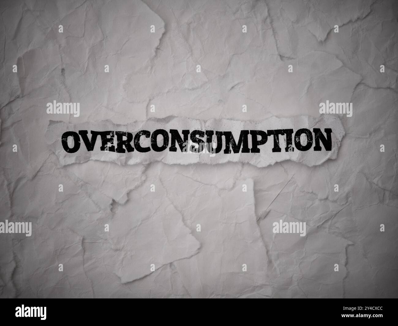Crumpled piece of paper with words Overconsumption on a torn white ...