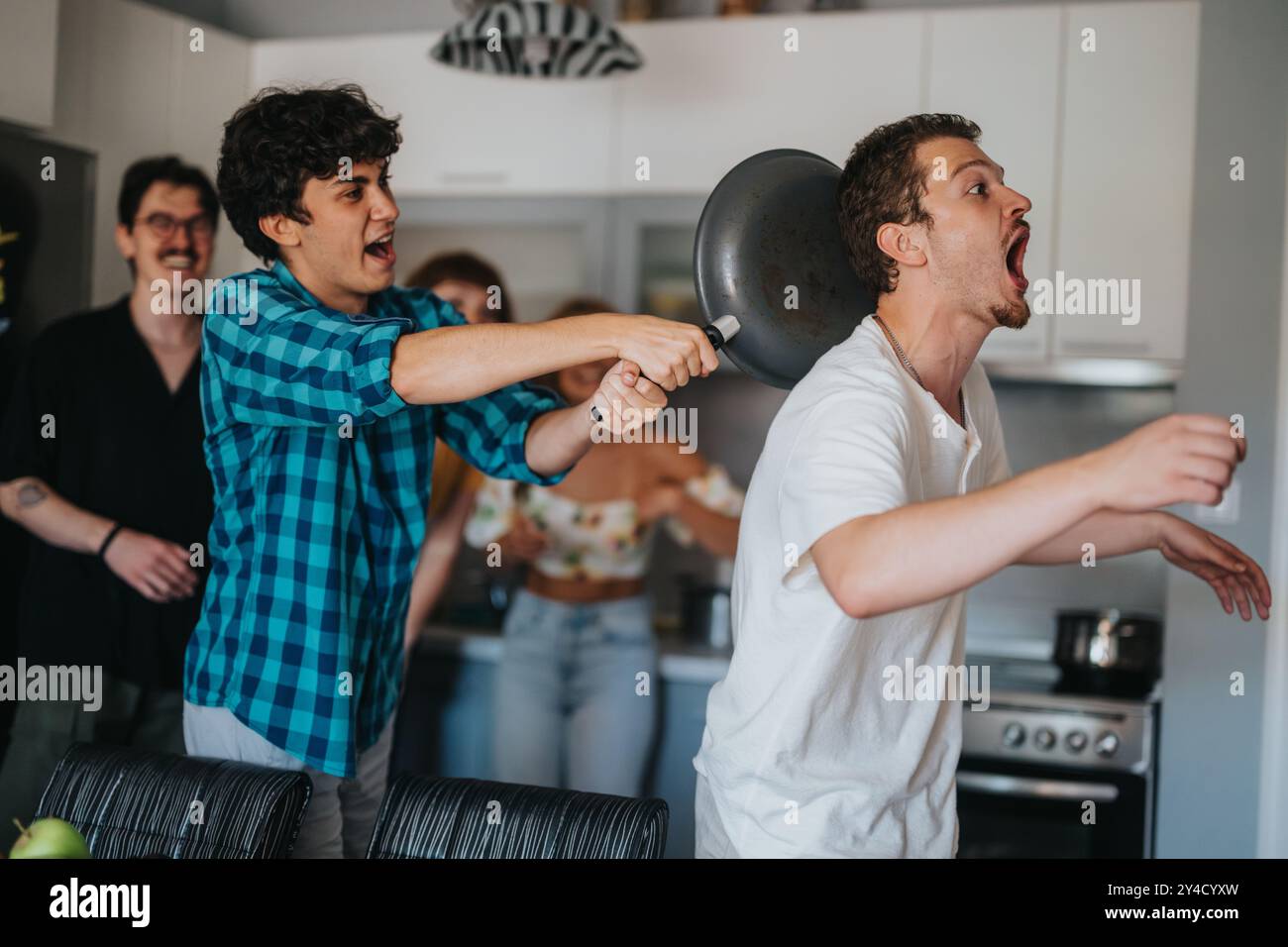 Friends having fun in the kitchen with a playful moment Stock Photo - Alamy