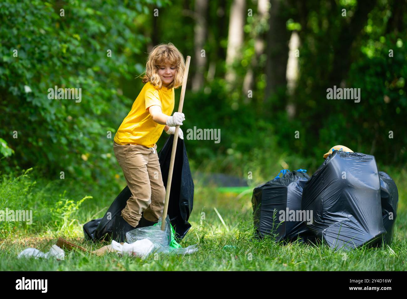 Kid cleaning up the park, putting trash in a garbage bag. Environmental ...