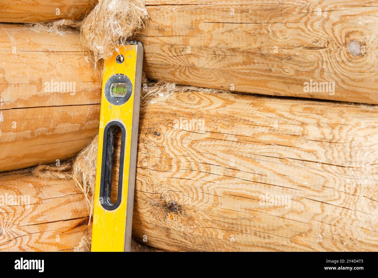 Yellow box beam level stands in the corner of new log house under ...