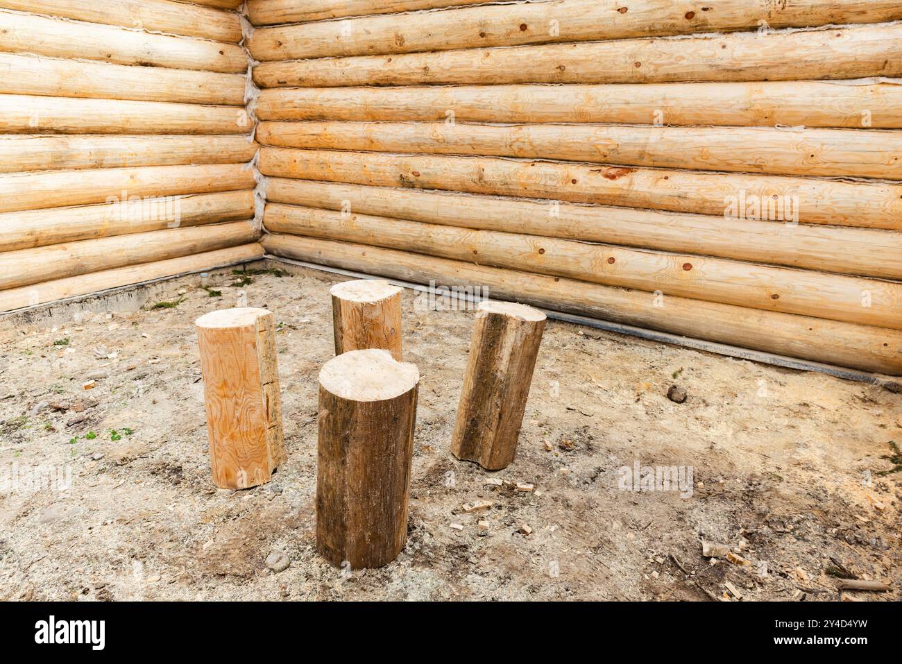 Four logs stand on the earthen floor in empty interior of a new wooden ...