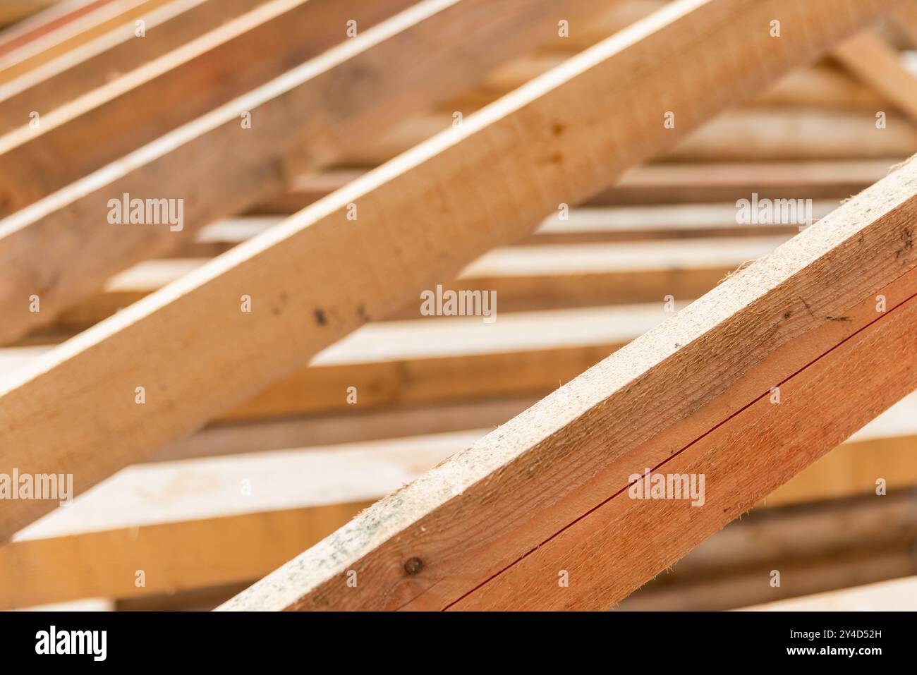 Wooden house roof is under construction. Rafters and beams are in a row ...