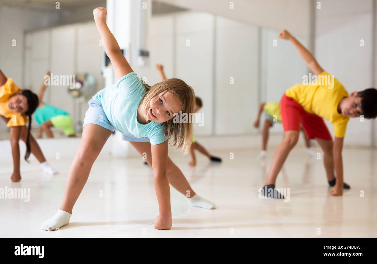 Little girl doing stretching exercises before training in dance class ...