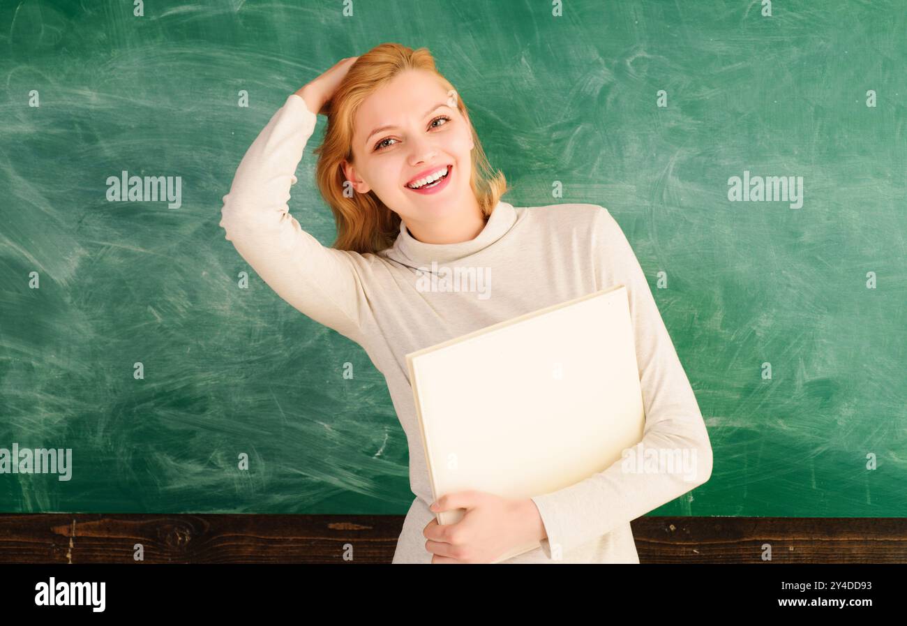 Smiling female teacher or student in front of chalkboard with class ...