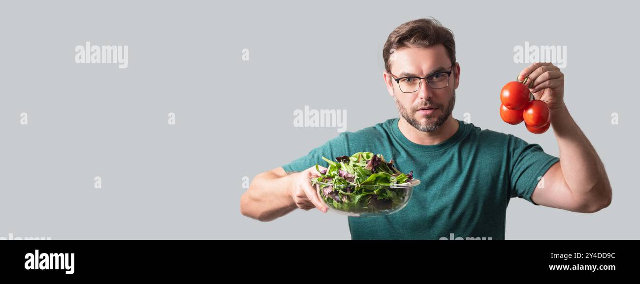 Man hold fresh tomato and vegetable salad isolated on gray background ...