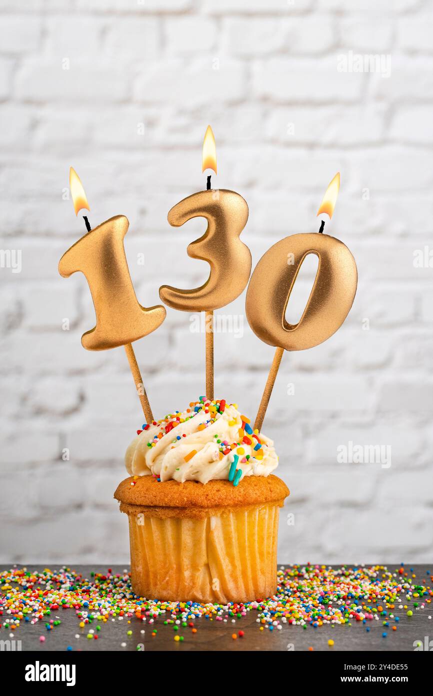 Cupcake with number 130 birthday candle - White block wall background ...