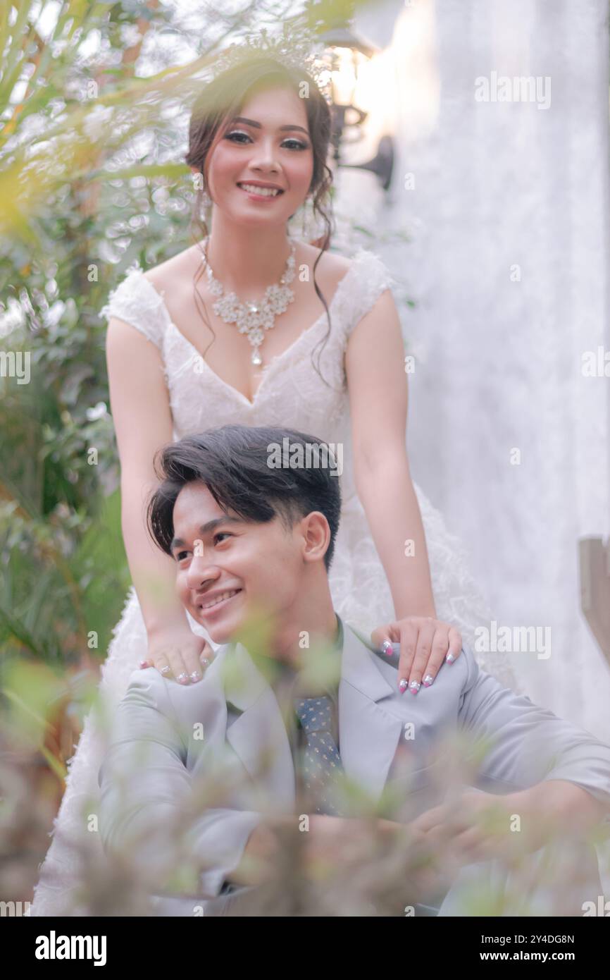 a pair of man and woman pose elegantly woman standing and man sitting ...