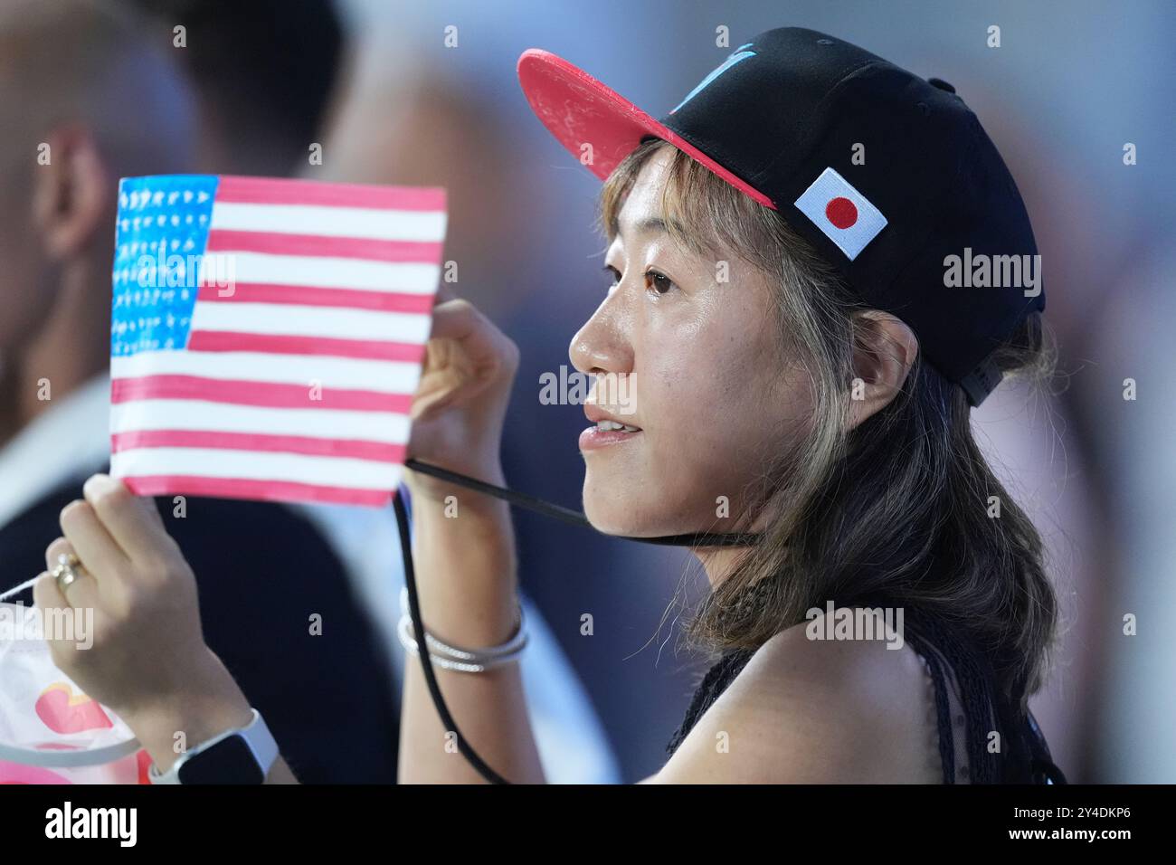 A baseball fan waves an American flag during the singing of the ...