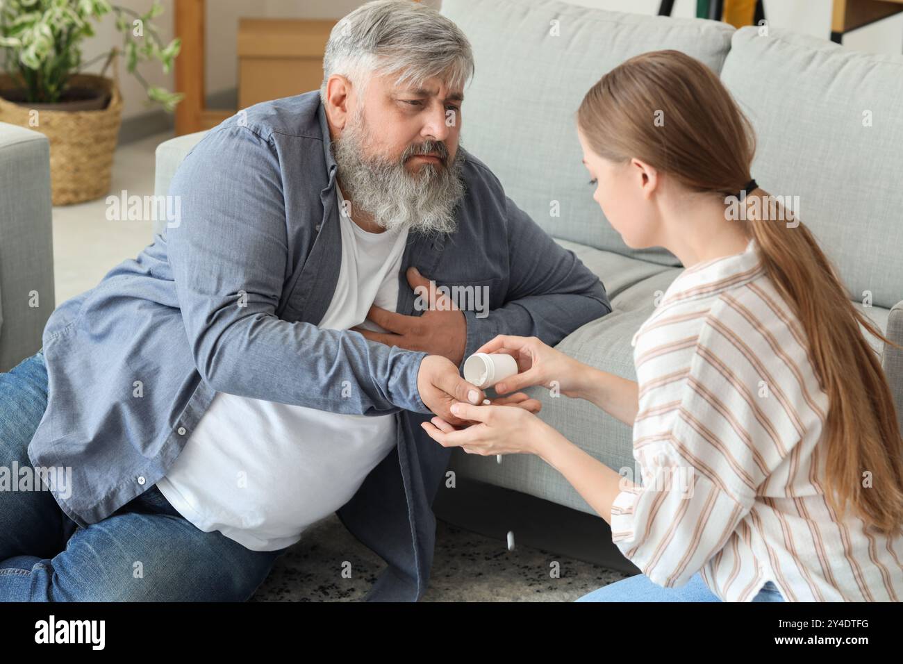 Young woman giving medicine to her father who is having heart attack at ...