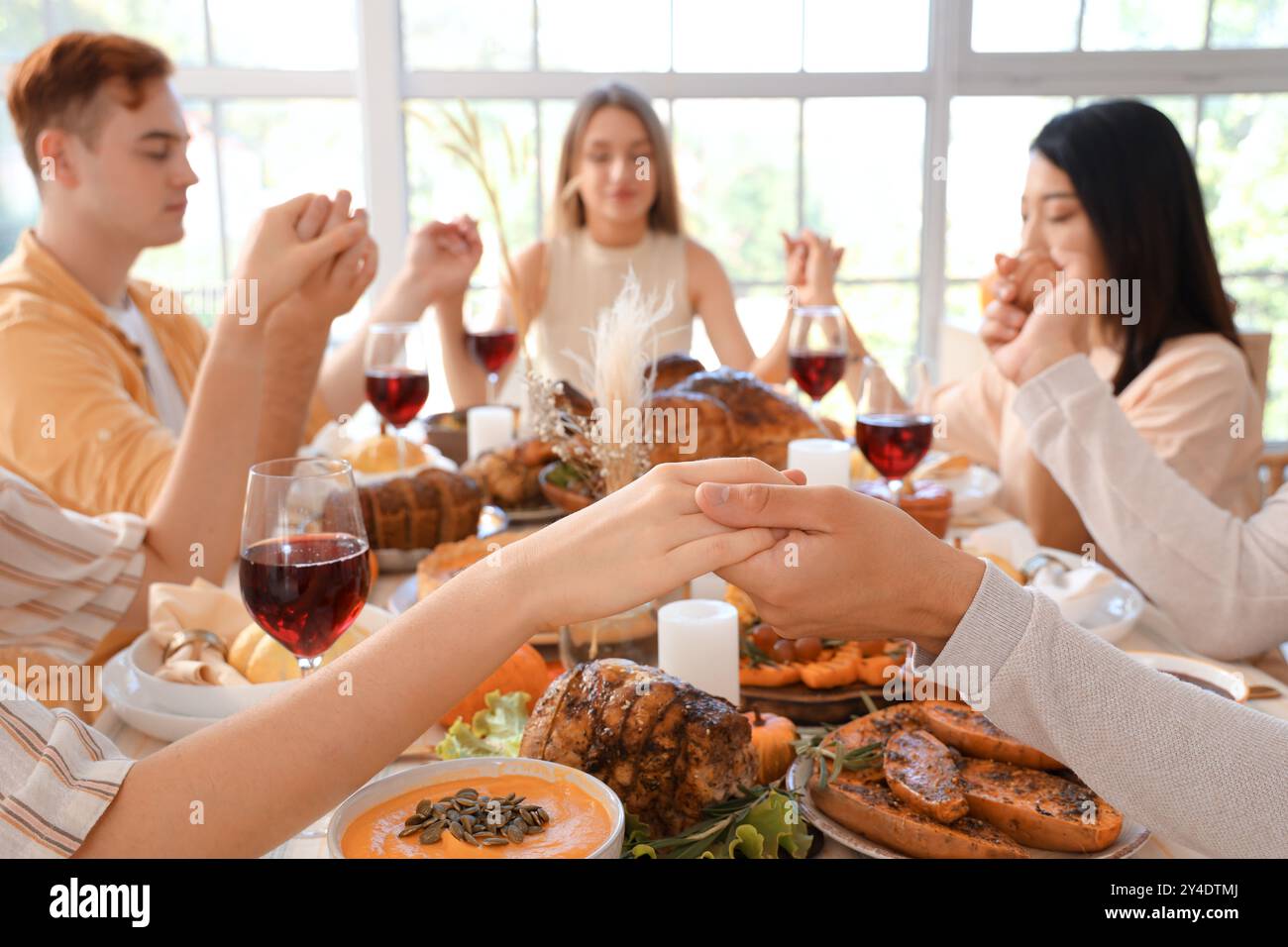 Group of young friends praying before dinner at festive table on ...