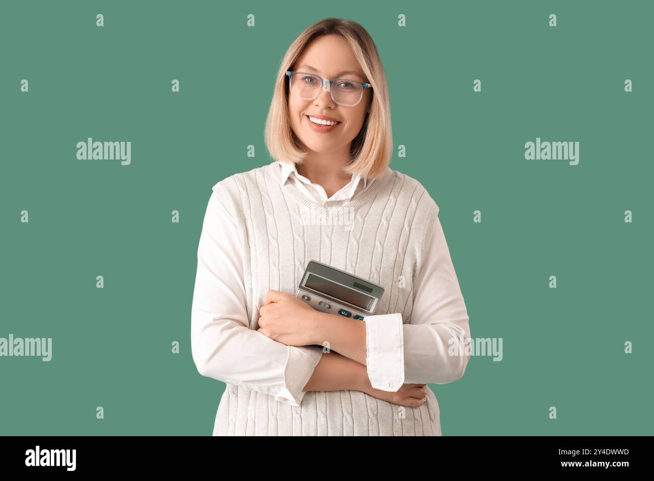 Mature female math teacher with calculator on green background Stock ...