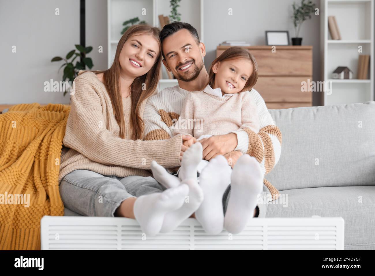 Little girl with her parents warming feet on radiator at home Stock ...