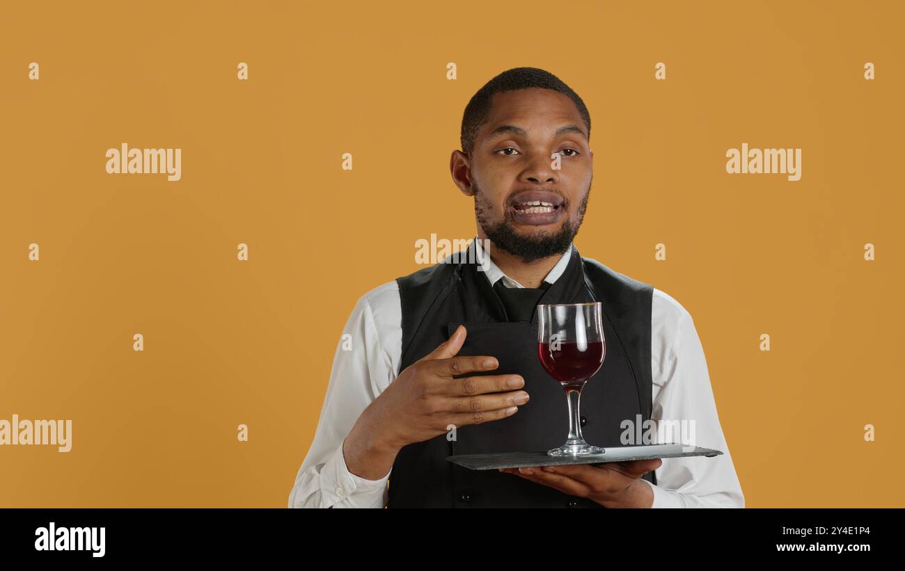 Waiter serving clients with a glass of red wine before dinner ...