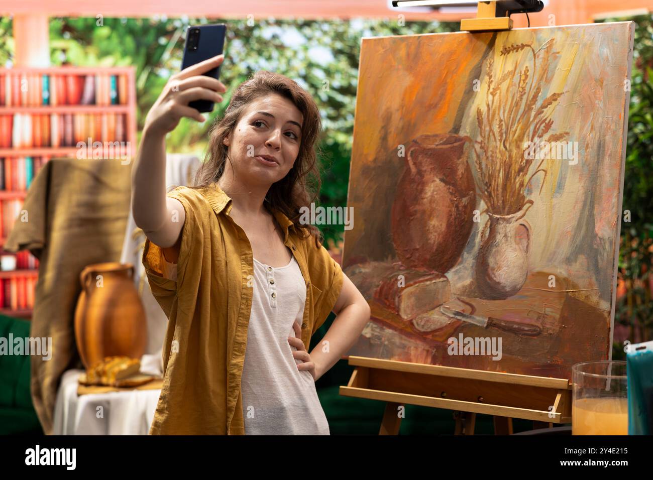 In a modern atelier, artist is filming her rustic artwork painting with ...