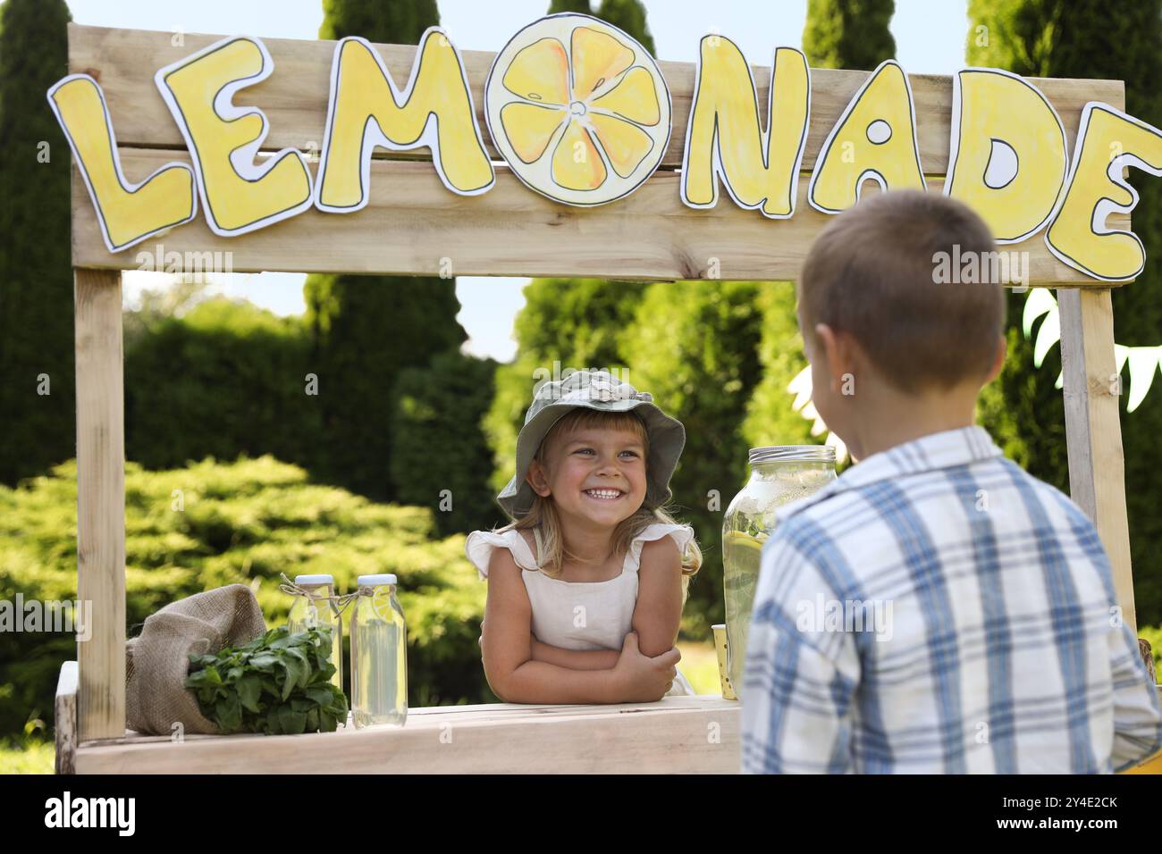 Cute little girl selling natural lemonade to boy in park Stock Photo ...