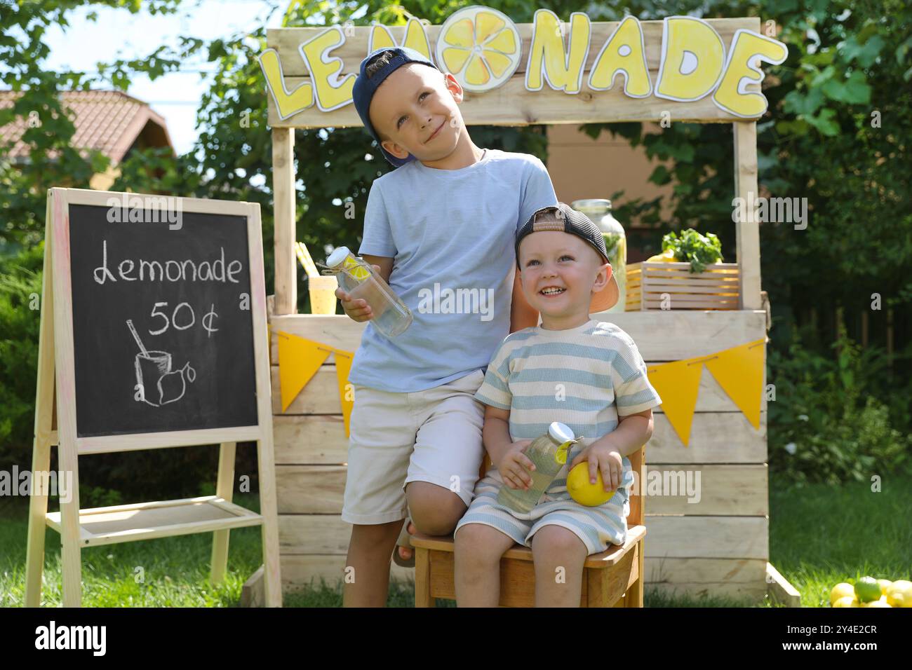 Cute boys with refreshing drinks near lemonade stand in park Stock ...