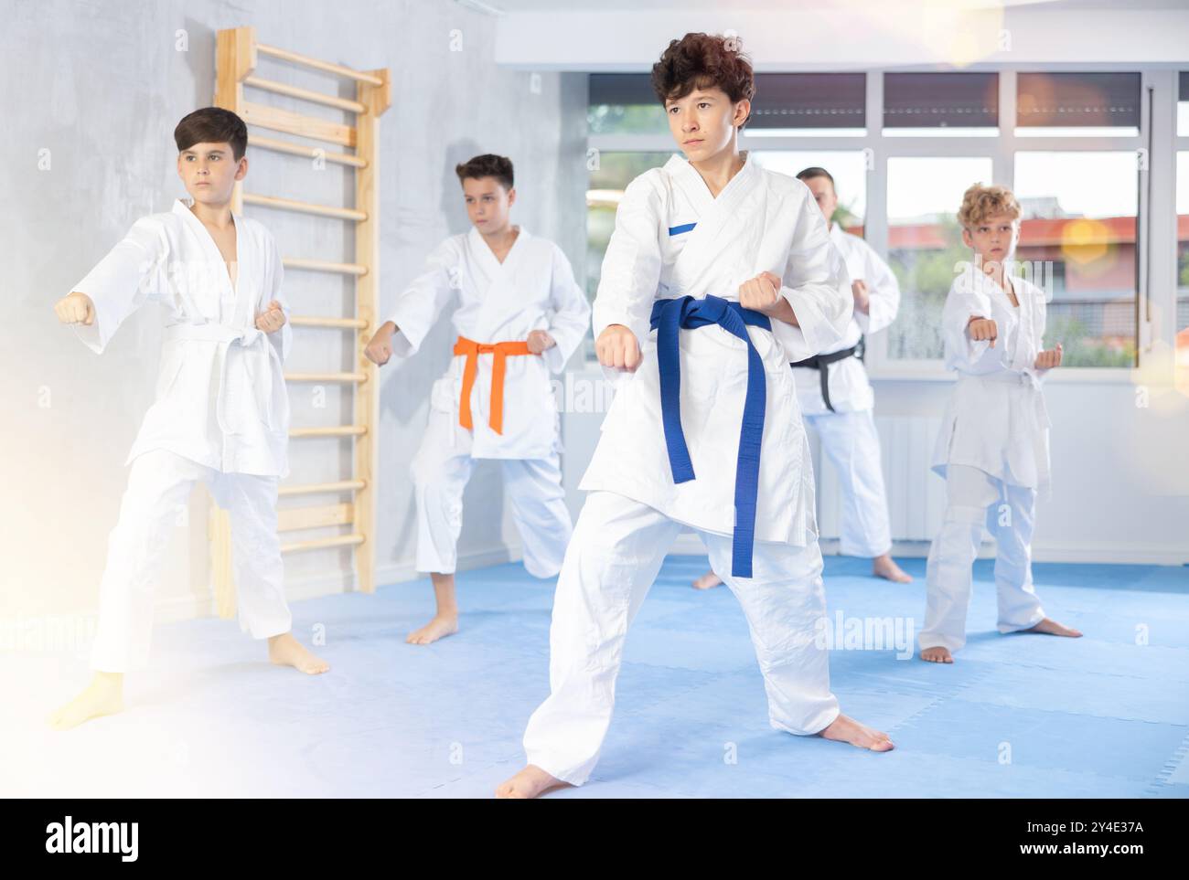 Teenage boy with group of karate practitioners performing kata routines ...