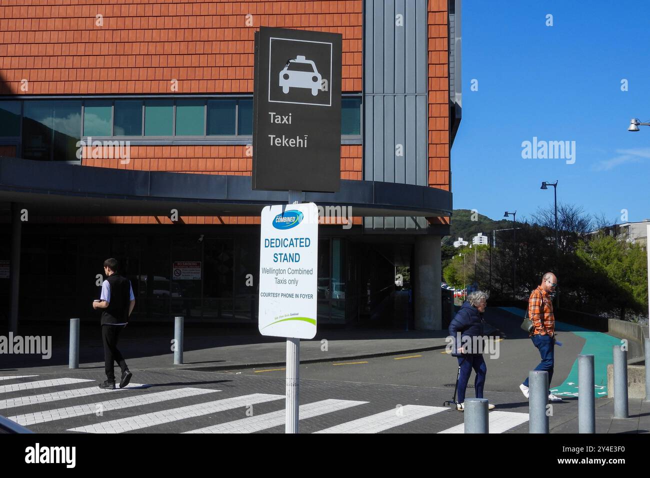 People cross a road near a taxi stand written in English and Maori ...