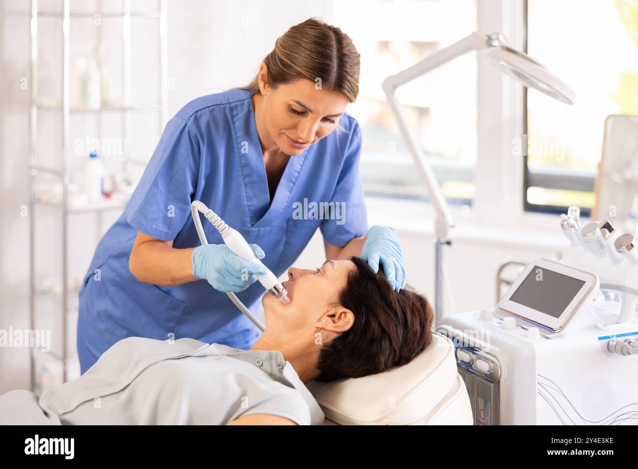 Woman doctor doing facial deep hydration procedure on elderly female ...