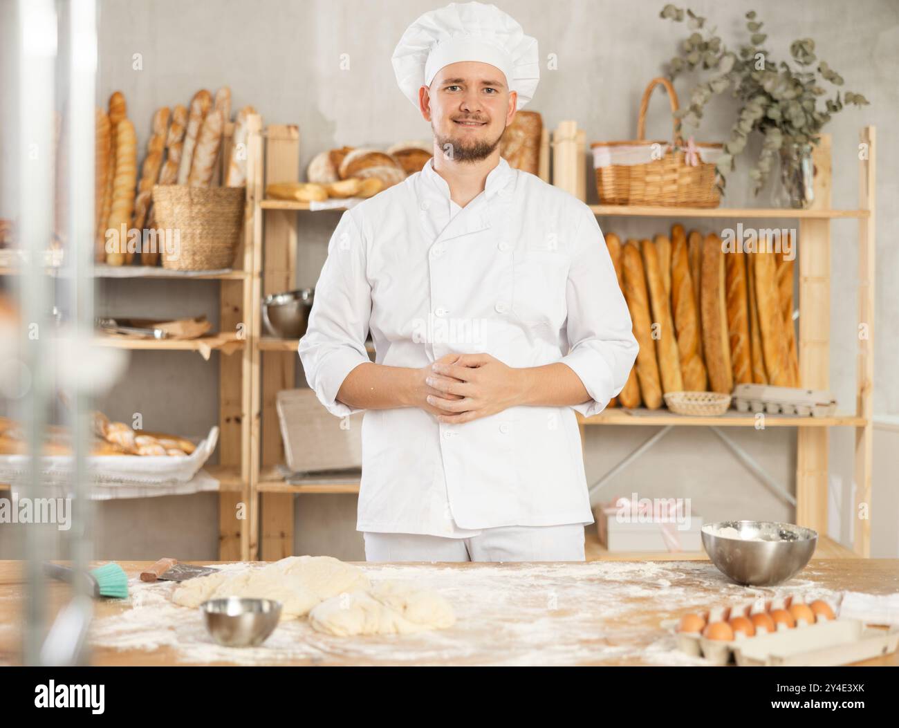 Male baker stands near work table in bakery, resting while working ...
