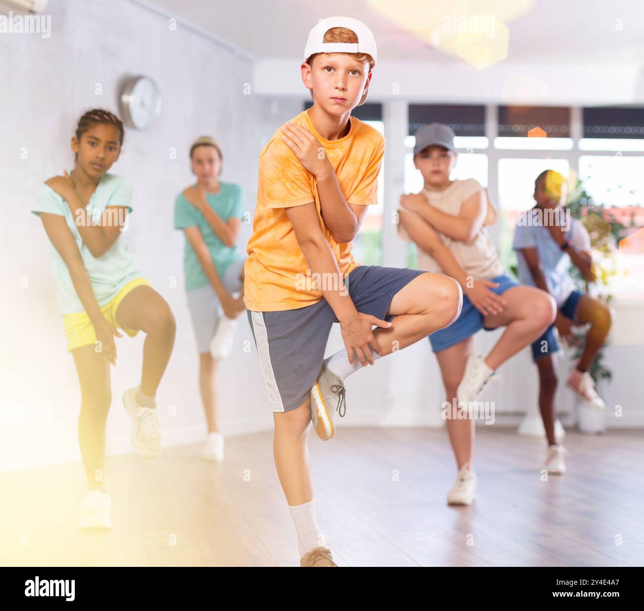 Expressive tween boy practicing hip-hop movements during group dance ...