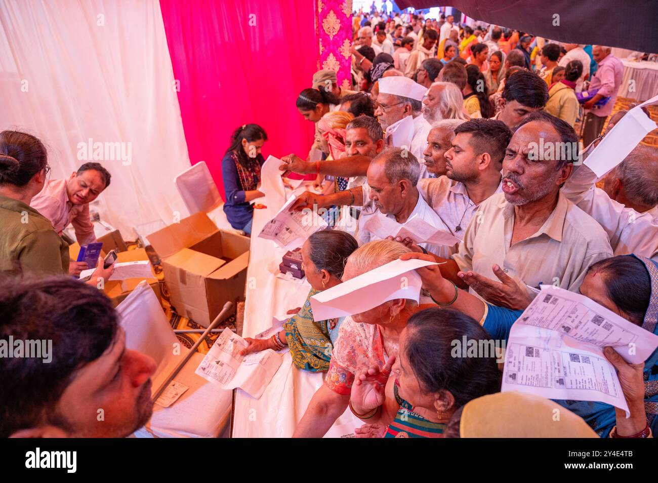 Beneficiaries hold documents at the crowded distribution counter ...