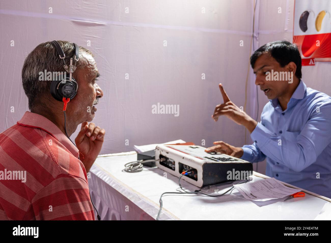 A professional is conducting a hearing test for a man during massive ...