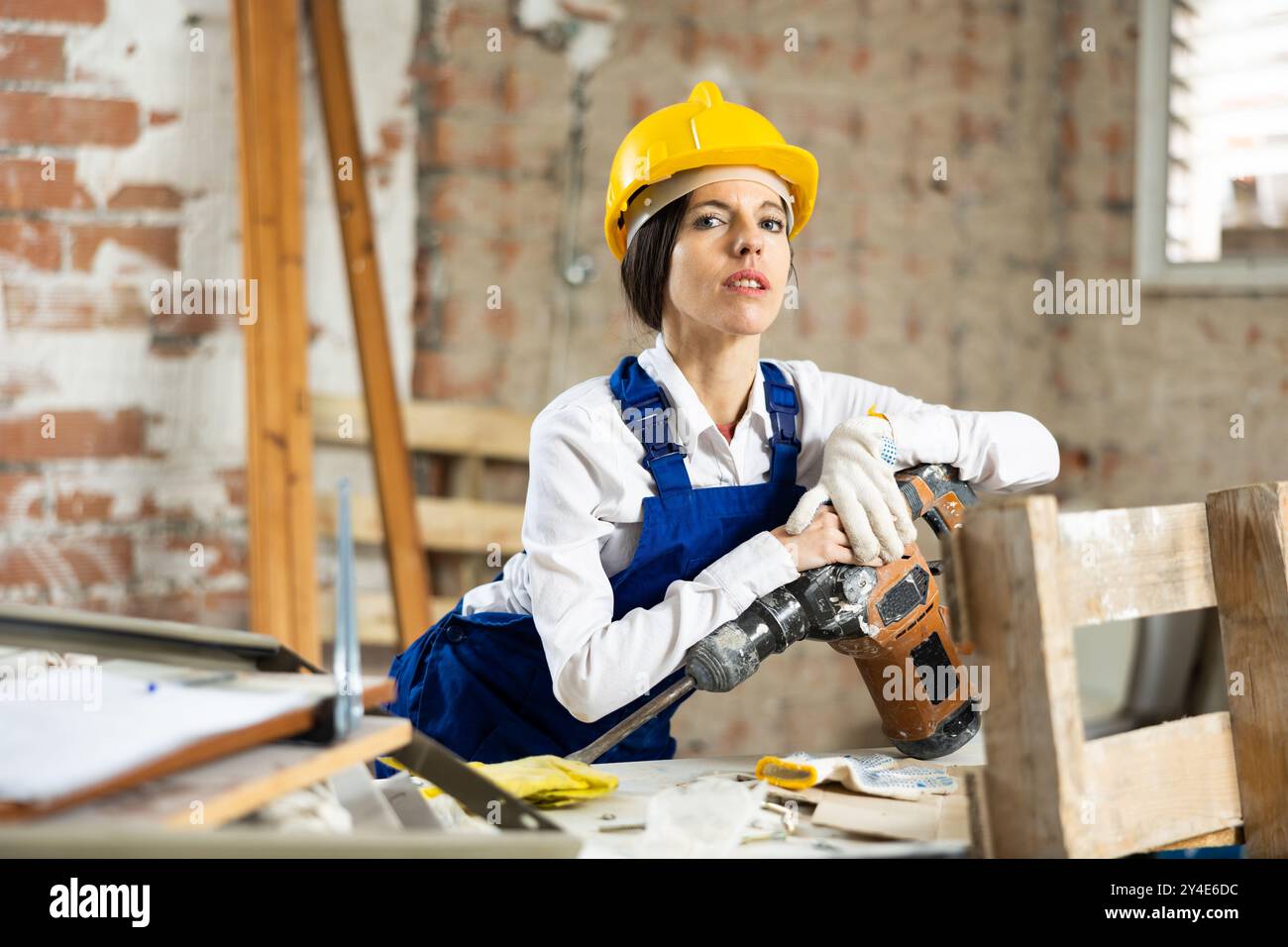 Female contractor standing with pneumatic demolition hammer at ...