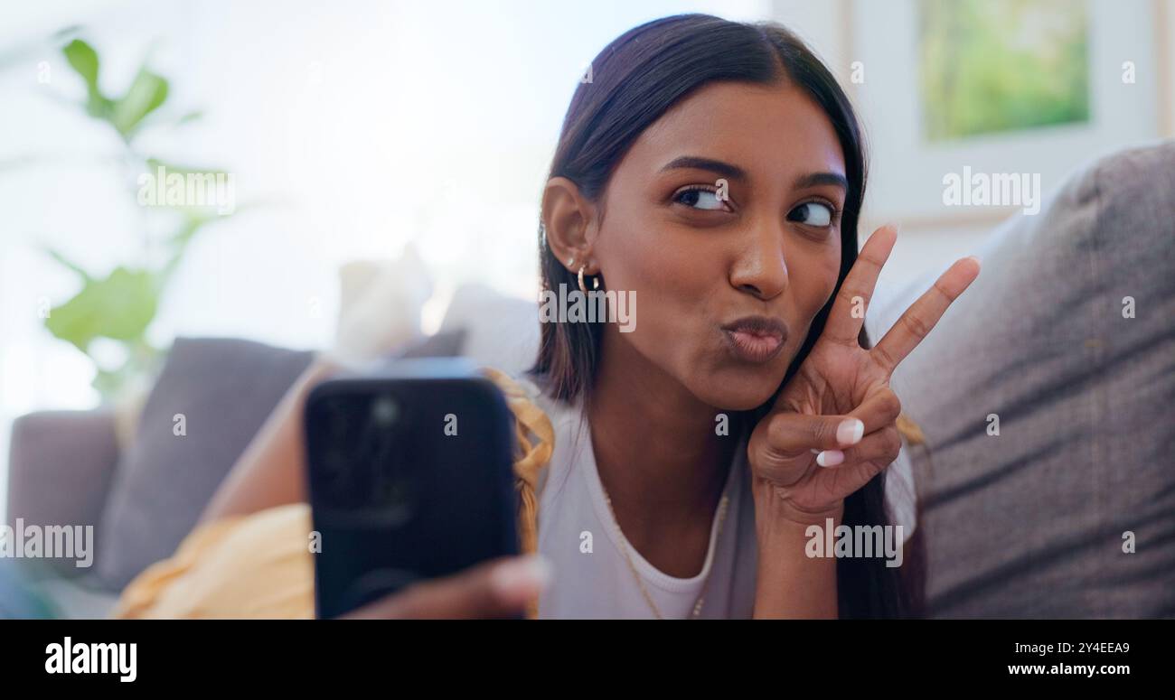 Sofa, funny face and woman in selfie with peace sign for social media ...