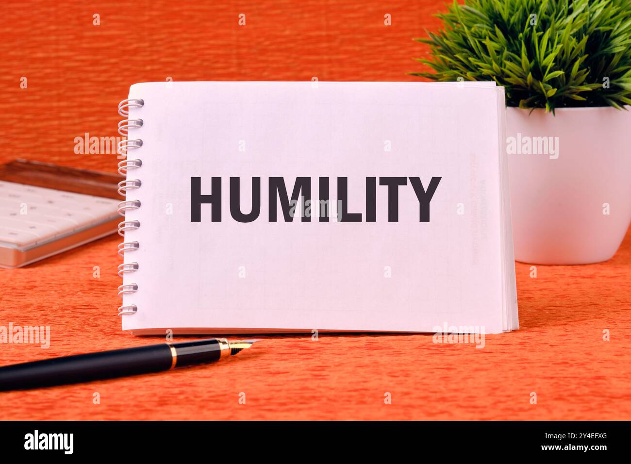 Lifestyle concept. HUMILITY word on a blank notepad page on an orange ...