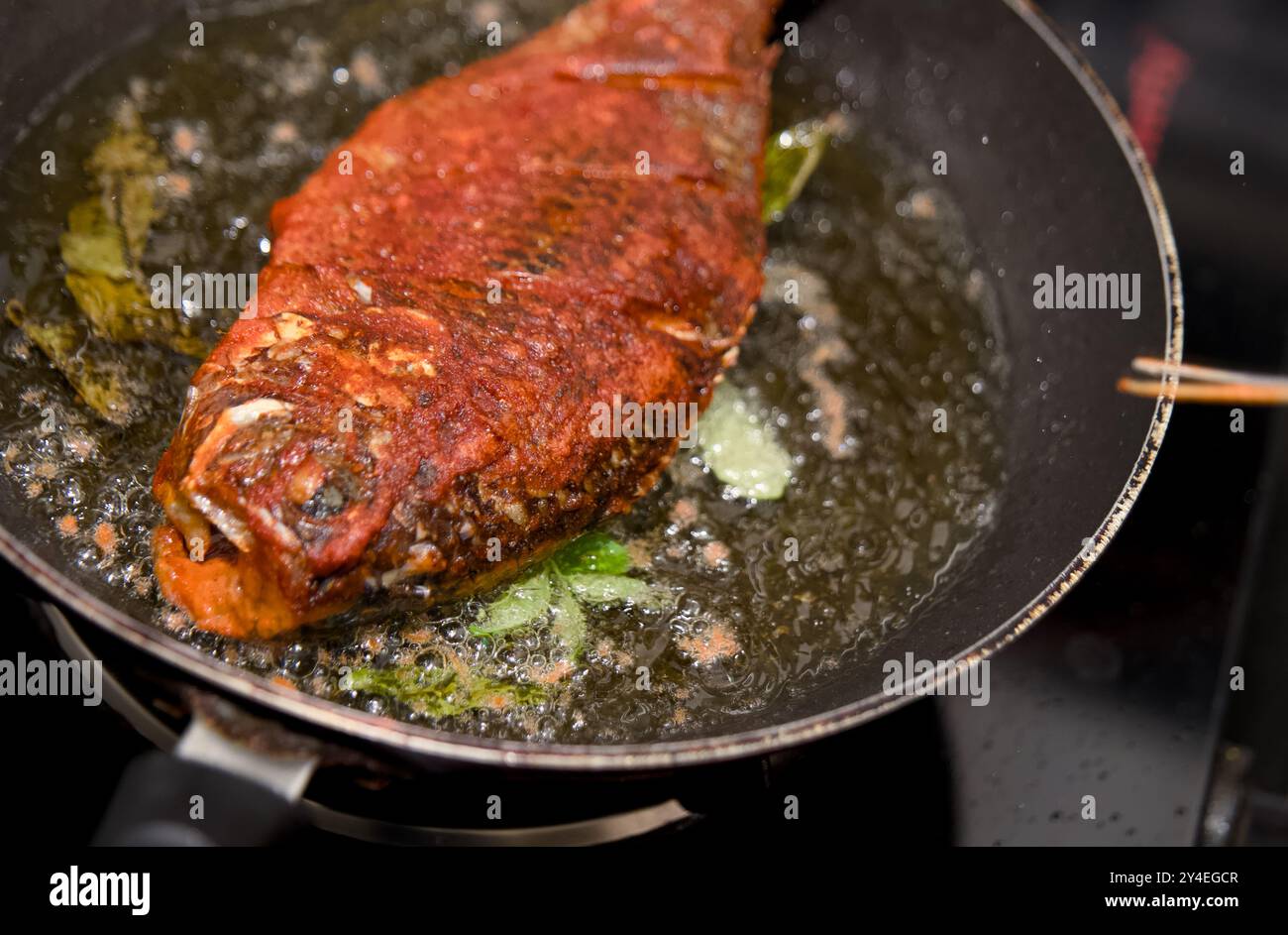 Delicious whole fish frying to perfection in a pan with hot oil, bay ...