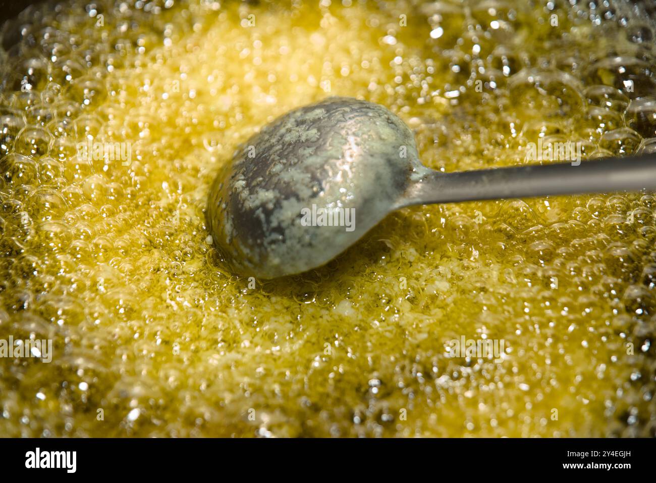 Golden bubbles dance in hot Ghee, a weathered spoon at the edge hinting ...