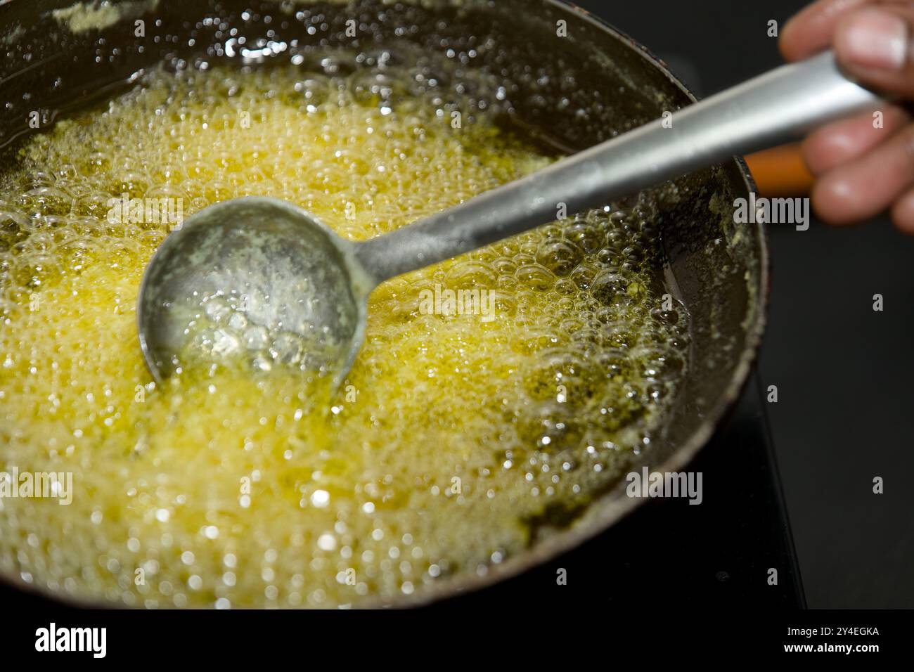 Golden bubbles rise in hot Ghee as a chef checks for cooking ...
